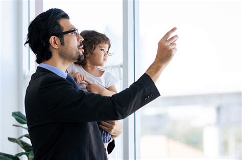 백인 잘 생긴 아버지는 안경과 정장 정장을 입고 어린 딸을 태우고 사무실 의 창문 근처에 서있는 동안 밖으로 포잉합니다 교육 및 가족 개념 2명에 대한 스톡 사진 및 기타