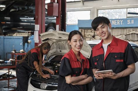 Two Asian Professional Automotive Mechanics Working At A Service Garage