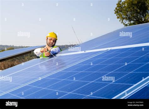 Young Indian Worker Technician Installing Heavy Solar Panels Outdoors