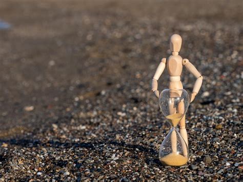 Premium Photo Wooden Stick Figure Next To Hourglass On The Beach At
