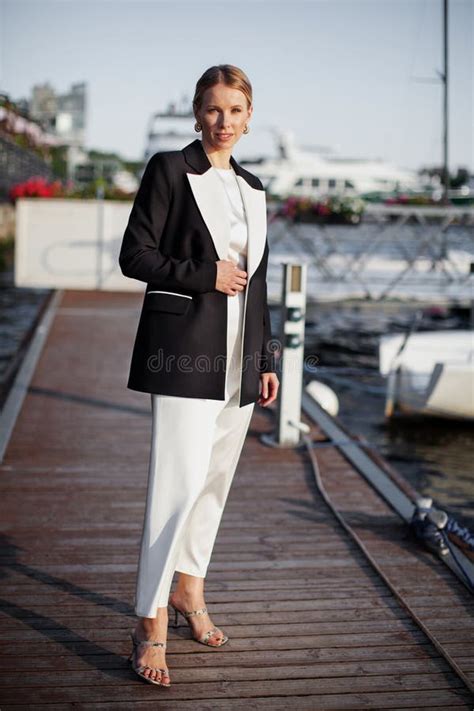 Fashion Model Strikes A Pose On A Pier Near Water Adorned In Luxurious