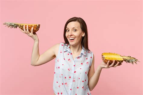 여름 옷에 흥분 젊은 여자 분홍색 파스텔 배경에 고립 된 신선한 잘 익은 파인애플 과일의 Halfs와 손을 확산 사람들은 생생한