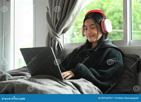 Happy Teenage Girl In Headphones Watching Movie Or Surfing Internet On