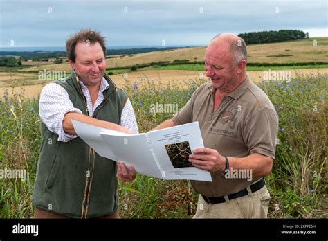 Land Agent And Farmer Discussing Farm Management On An Arable Farm In