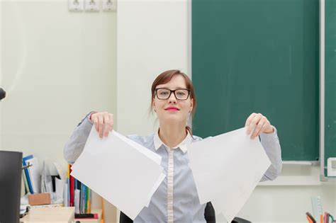 작업을 완료 한 후 그녀의 손에 문서를 들고 테이블에 앉아 그녀의 직장에서 귀여운 여자 교사 30 34세에 대한 스톡 사진 및
