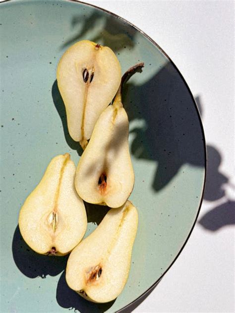 도자기 접시에 놓인 배 반쪽에 드리운 그림자 · 무료 스톡 사진