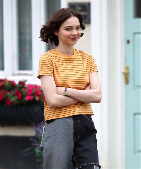 A Woman Standing In Front Of A Door With Her Arms Crossed