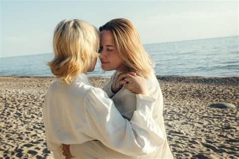 Mom And Daughter Are Standing On The Beach By The Sea Hugging Stock