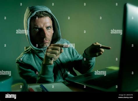 Dangerous Looking Hacker Man In Hoodie Hacking Internet Computer System Pointing His Eyes