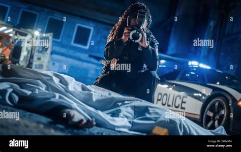 Black Female Police Officer Using Camera With Flash To Take Photos Of A
