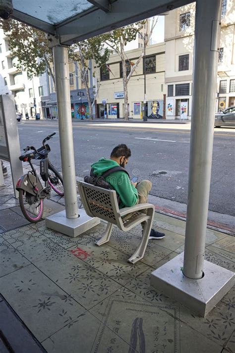 Young Man Using Smartphone Waiting For Bus At Bus Stop Editorial Stock