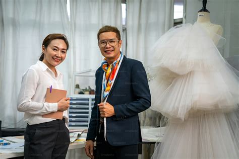 웃고 있는 아시아 Lgbtq 남자 신부 가게 주인이 웨딩 스튜디오의 사무실에서 여성 조수와 함께 일하는 초상화 중소 기업