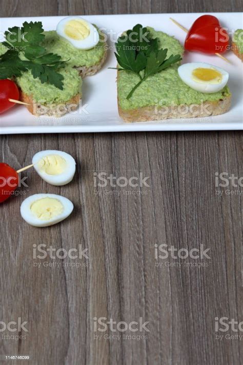 아침 식사 샌드위치 아보카도가 묻어 있는 하트 모양의 빵 슬라이스 삶은 메 추리 알 파 슬 리 토마토로 장식 되어 있습니다 흰색