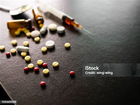 Narcotics Concept Ecstasy Pills And Syringe On Black Wooden Table