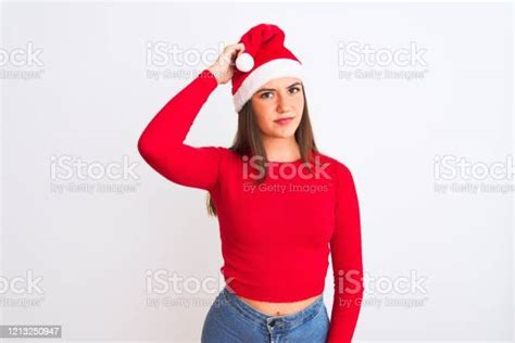 고립 된 흰색 배경 위에 서 크리스마스 산타 모자를 입고 젊은 아름다운 소녀는 혼란에 질문에 대한 궁금 의심의 여지가 머리에 손으로 생각 펜시브 개념 12월에 대한 스톡