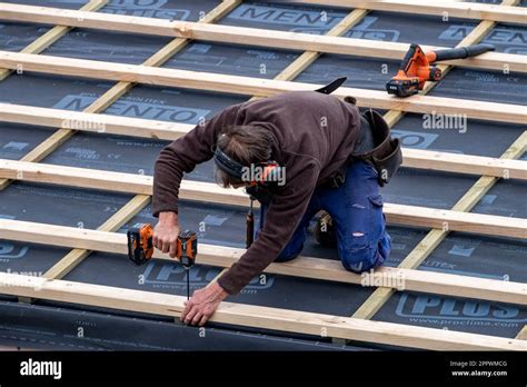 Tradesman Fastening Timber Roof Battens Over Insulation On A Home