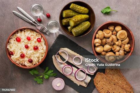 전통적인 러시아 간식 및 보드카 크랜베리 청 어 절인 오이 절인 버섯과 호 밀 빵과 갈색 배경에 소금에 절인 양배추 평면도