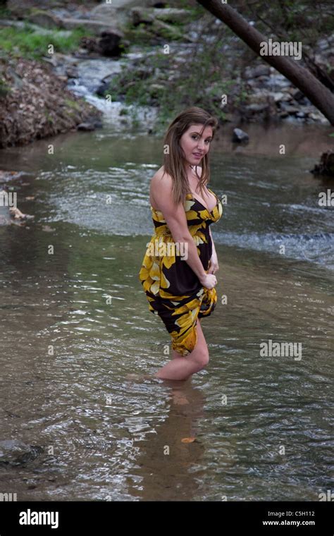 Jolie Femme En Robe Jaune De Patauger Dans Un Ruisseau Peu Profond