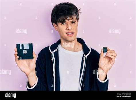 Handsome Hipster Young Man Holding Floppy Disk And Sdxc Card Clueless