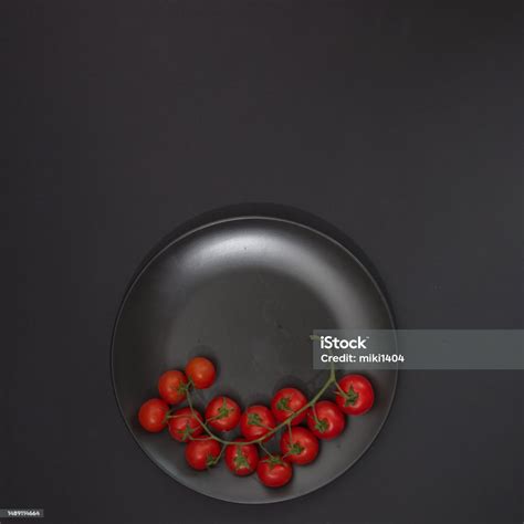 육즙이 많은 빨간 방울 토마토는 날카로운 검은색 배경에 검은색 접시에 복사 공간이 있습니다 최소한의 야채 성분 건강한 생활방식에