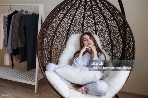 여자는 고치의 자에 있는 잠 옷에 앉 았다 방의 세련 된 인테리어 소녀는 그 여자를 흔들어 긴에 대한 스톡 사진 및 기타 이미지 Istock