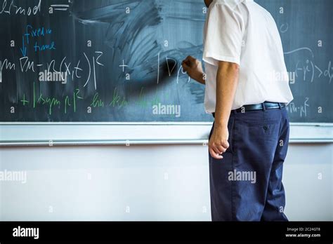Teacher Teaching Mathematics While Pointing At Blackboard In Classroom Stock Photo Alamy