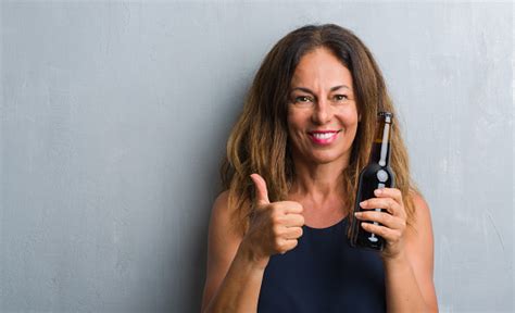 중세 스페인 여자 회색 그런 지 벽 행복 큰 맥주 병을 들고 서 확인 서명 하 고 미소 손가락 우수한 로그인으로 엄지 갈색