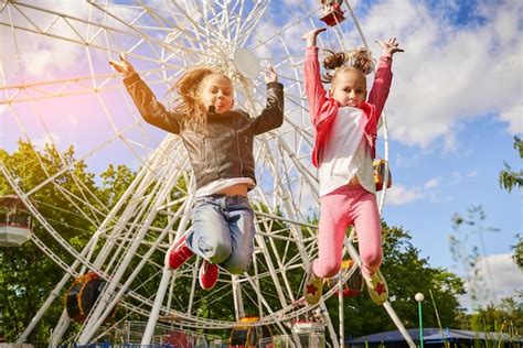 Deux Filles S Amusent Dans Un Parc D Attractions Une Grande Roue Est En Arri Re Plan Photo Premium
