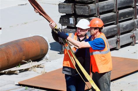 Premium Photo Two Helmeted Slingers Attach Load To Slings Outside On