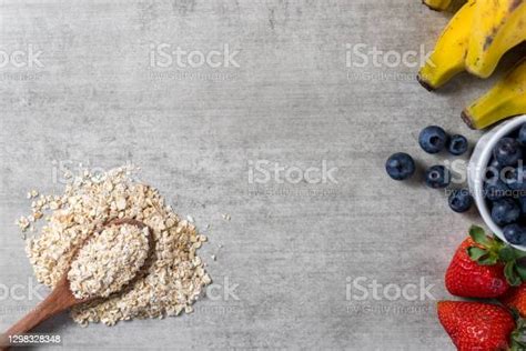 귀리로 가득 찬 숟가락과 나무 테이블에 신선한 건강한 과일이있는 배경 바나나 블루베리 딸기 맨 위 보기입니다 공간을 복사합니다