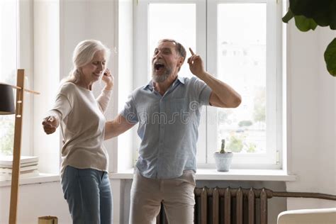 Joyful Excited Mature Retired Couple Having Fun At Home Party Stock