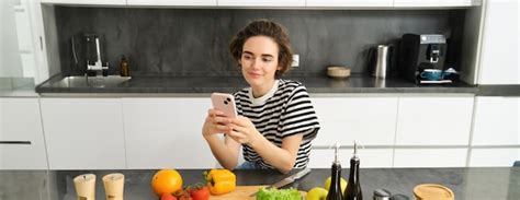 Porträt Einer Jungen Frau Mit Smartphone Die In Der Küche Sitzt Und