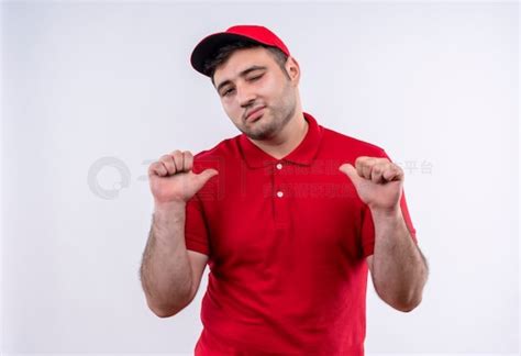 年轻高清图片 身穿红色制服、头戴帽子的年轻送货员用拇指指着自己，自信而自豪地站在白墙上 人像图片免费下载格式626像素编号