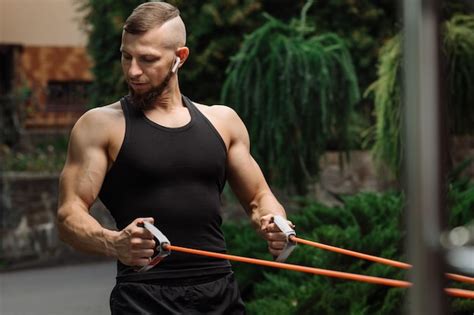 Premium Photo Muscular Fitness Coach Doing Exercises With Stretching Rubber Outdoors