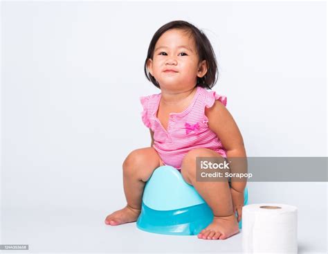 아시아 작은 귀여운 아기 소녀 교육 훈련 은 화장지 롤과 파란색 챔버 냄비 또는 변기에 앉아 흰색 배경에 고립 된 스튜디오 샷
