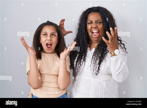 Mother And Young Daughter Standing Over White Background Crazy And Mad