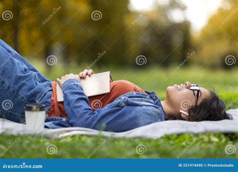 Outdoor Leisure Nerdy Arab Female In Eyeglasses Lying On Lawn With