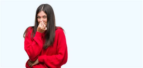 코에 빨간 스웨터 뭔가 냄새 나 고 역 겨 운 냄새 참을 냄새 손가락으로 잡고 호흡을 입고 젊은 아름 다운 스페인 나쁜 냄새 개념입니다 겨울에 대한 스톡 사진 및 기타