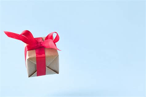 파란색 배경에 빨간색 리본이있는 선물 상자입니다 무중력 공중 부양 밀리멀리즘 카피 스페이스 컨셉 판매 쇼핑 크리스마스 휴일 및