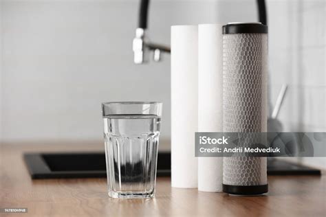 깨끗한 담수 한 잔과 주방 내부의 나무 테이블에 필터 카트리지 세트 역삼 투 정수 시스템 설치 개념 가정용 여과 시스템 수도