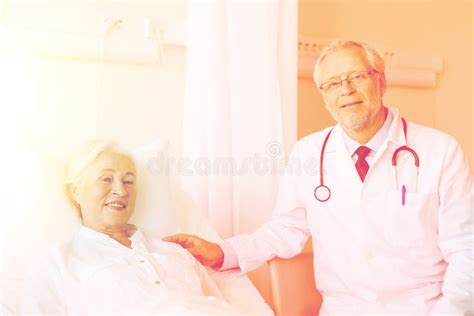 Doctor Que Visita A La Mujer Mayor En La Sala De Hospital Imagen De