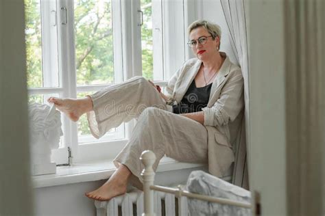 A Middle Aged Woman In A Beige Suit And Black Tank Top Sits