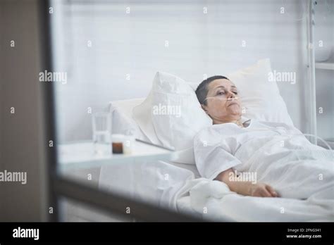 Mature Woman Lying On Hospital Bed Under Dropper At Hospital Stock