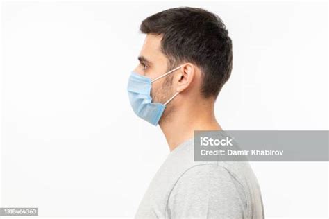 회색 배경에 고립 된 캐주얼 티셔츠와 얼굴 마스크를 착용한 젊은 남자의 왼쪽 보기 초상화 25 29세에 대한 스톡 사진 및 기타 이미지 25 29세 T 셔츠 건강