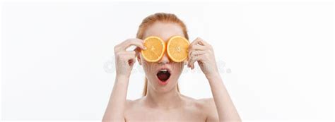 Portrait Of A Cheerful Young Girl Holding Two Slices Of An Orange At