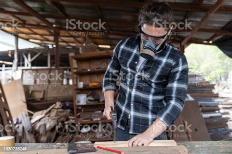 목조 보드에 못을 망치로 하고 목공 작업장에서 안전 고글과 먼지 필터 마스크를 착용하는 남성 목수 망치와 손톱을 사용하여 조이너는 나무 판자 고정 20 24세에 대한 스톡
