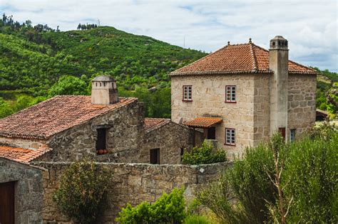 붉은 기와 지붕을 얹은 매력적인 소박한 석조 주택은 울창한 푸른 언덕 한가운데에 서 있어 고요한 시골 분위기와 전통적인 건축 양식을 발산합니다 0명에 대한 스톡 사진 및