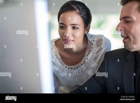 Businessman And Woman Looking At Personal Computer At Office Desk Stock