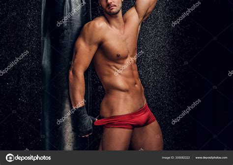 Hombre musculoso caliente con torso desnudo y saco de boxeo fotografía