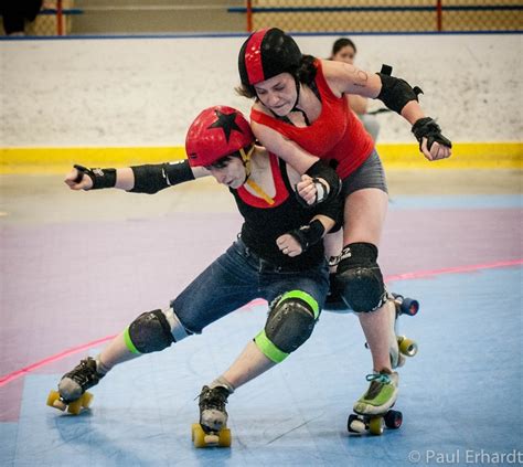 Two People On Roller Skates In An Indoor Rink One Is Holding The Other